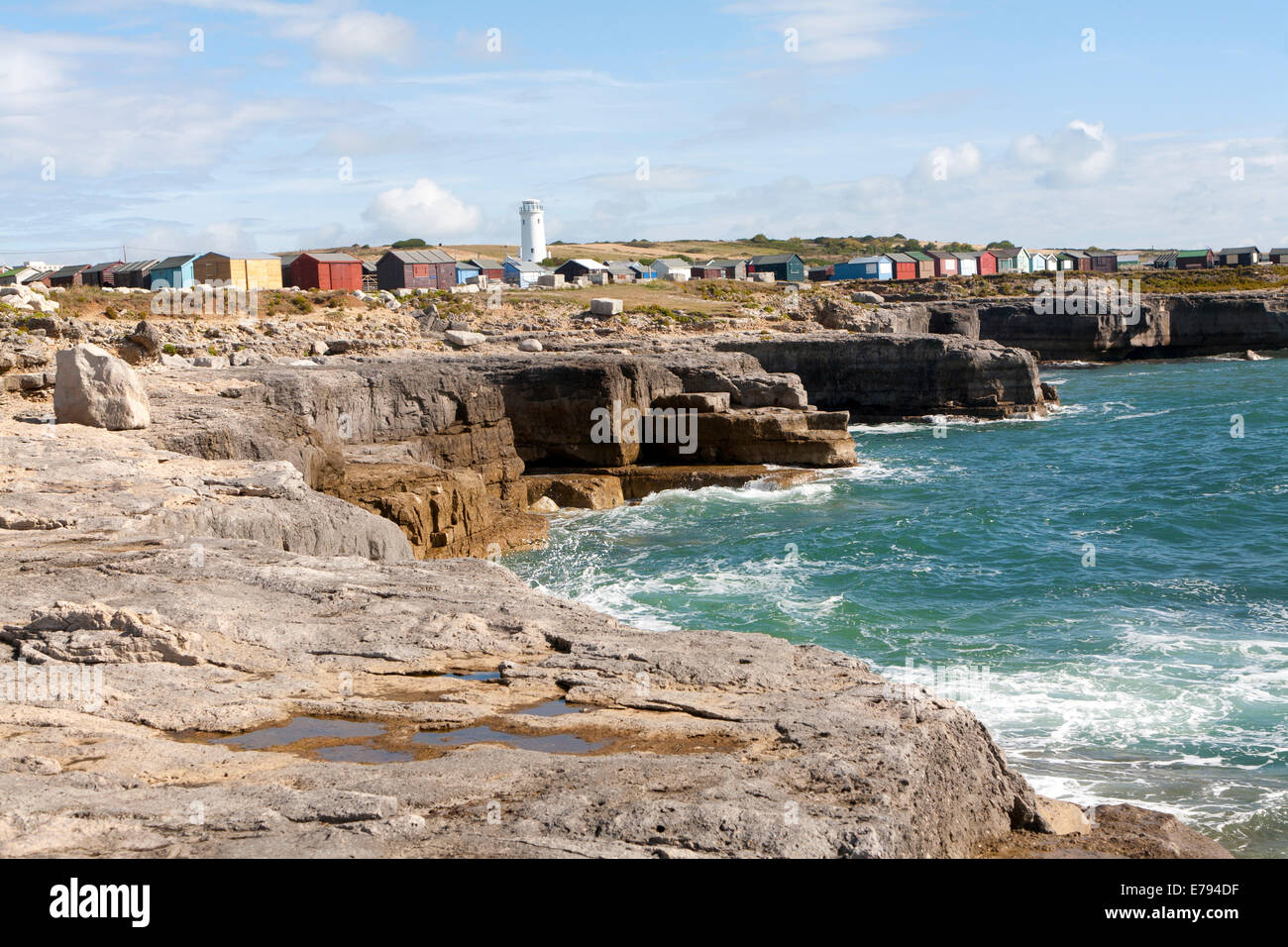 Old white lighthouse now a bird observatory and beach huts on the coast ...