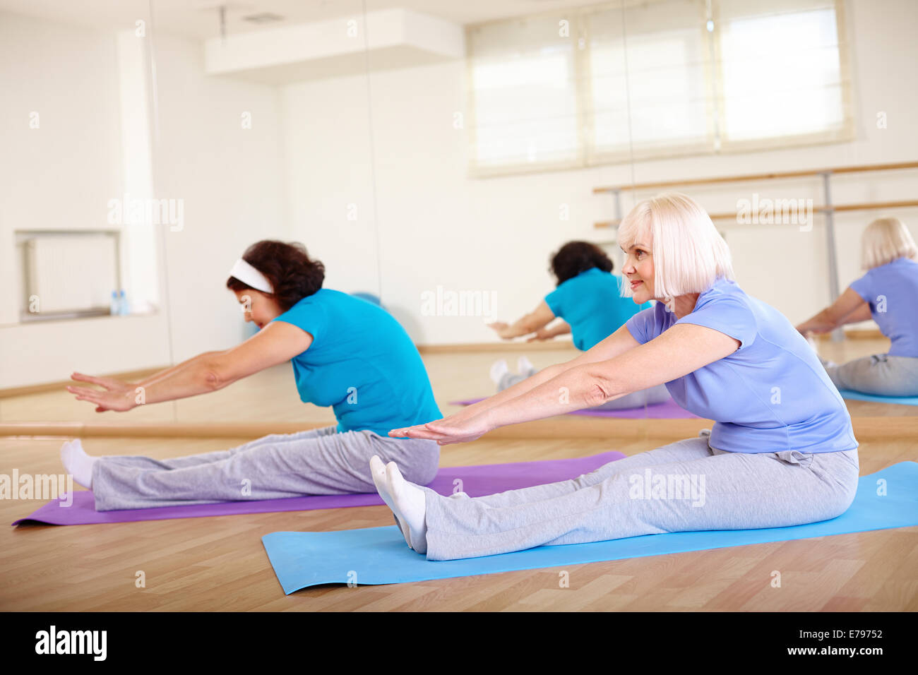 Portrait of mature females doing stretching exercise in sport gym Stock ...