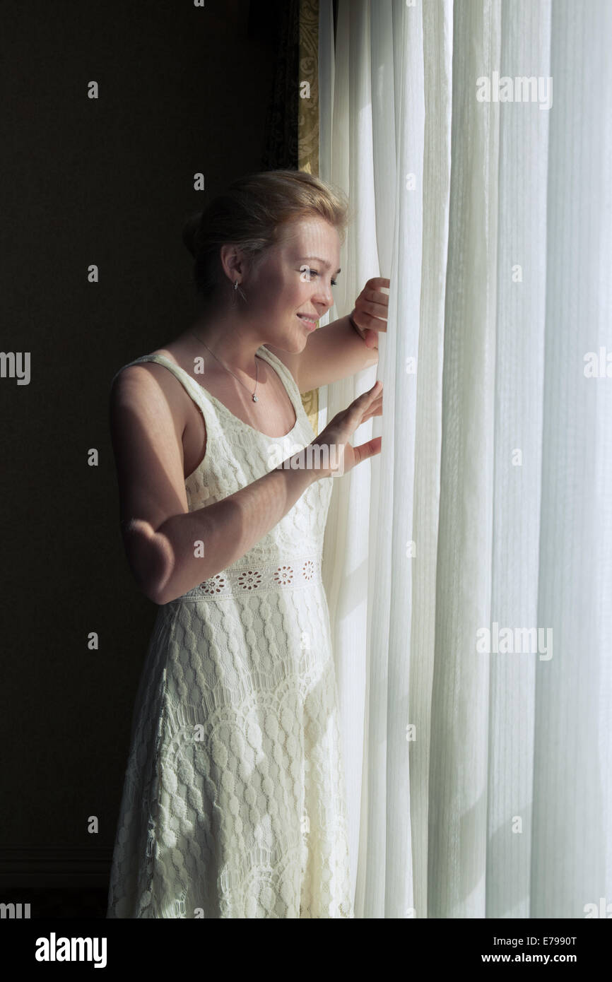 portrait of young beautiful woman looking in the window Stock Photo - Alamy