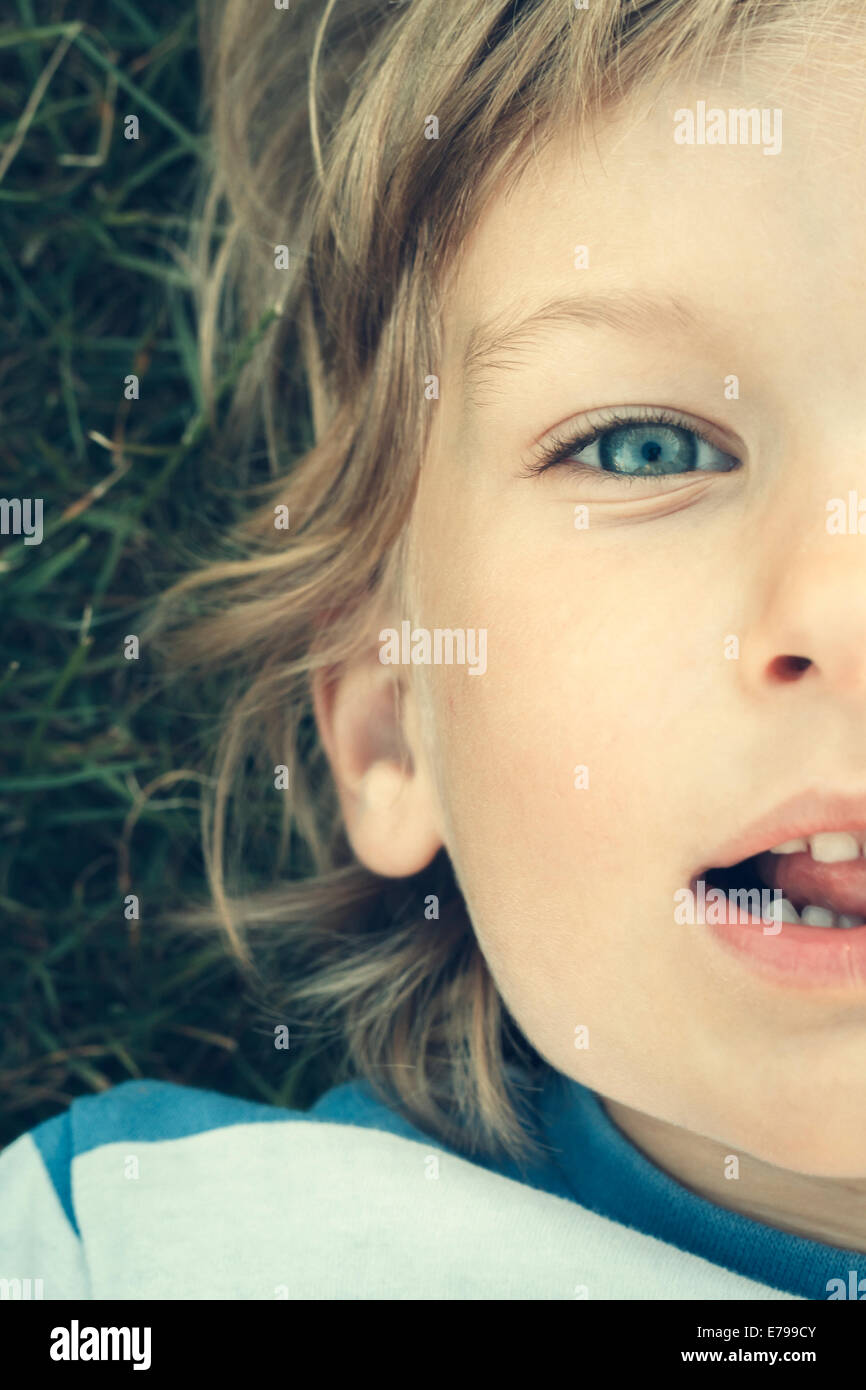 Young boy looking at camera while lying on back Stock Photo - Alamy