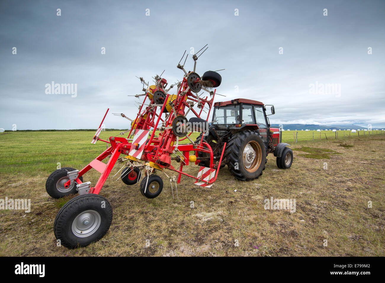 Red tractor in the field with a cloudy sky Stock Photo - Alamy