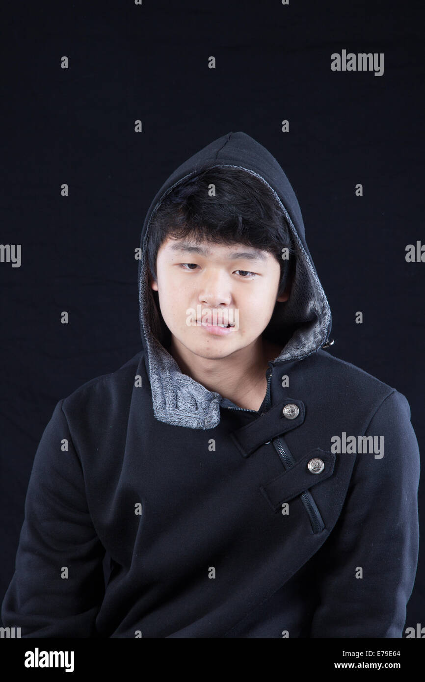 Asian man in a jacket, sitting and looking thoughtfully at the camera ...