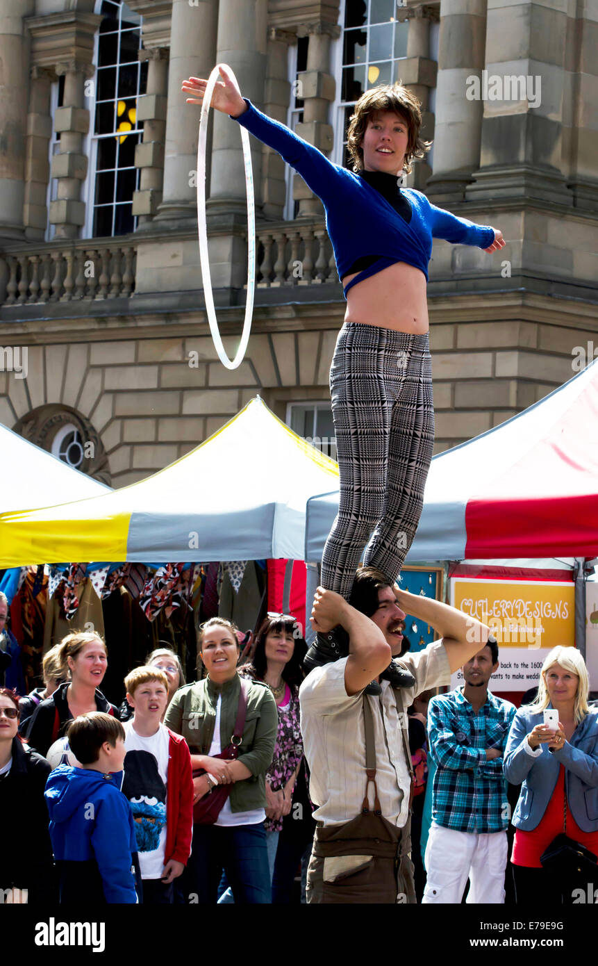 Young woman spinning a hoop whilst standing on a man's shoulders during ...