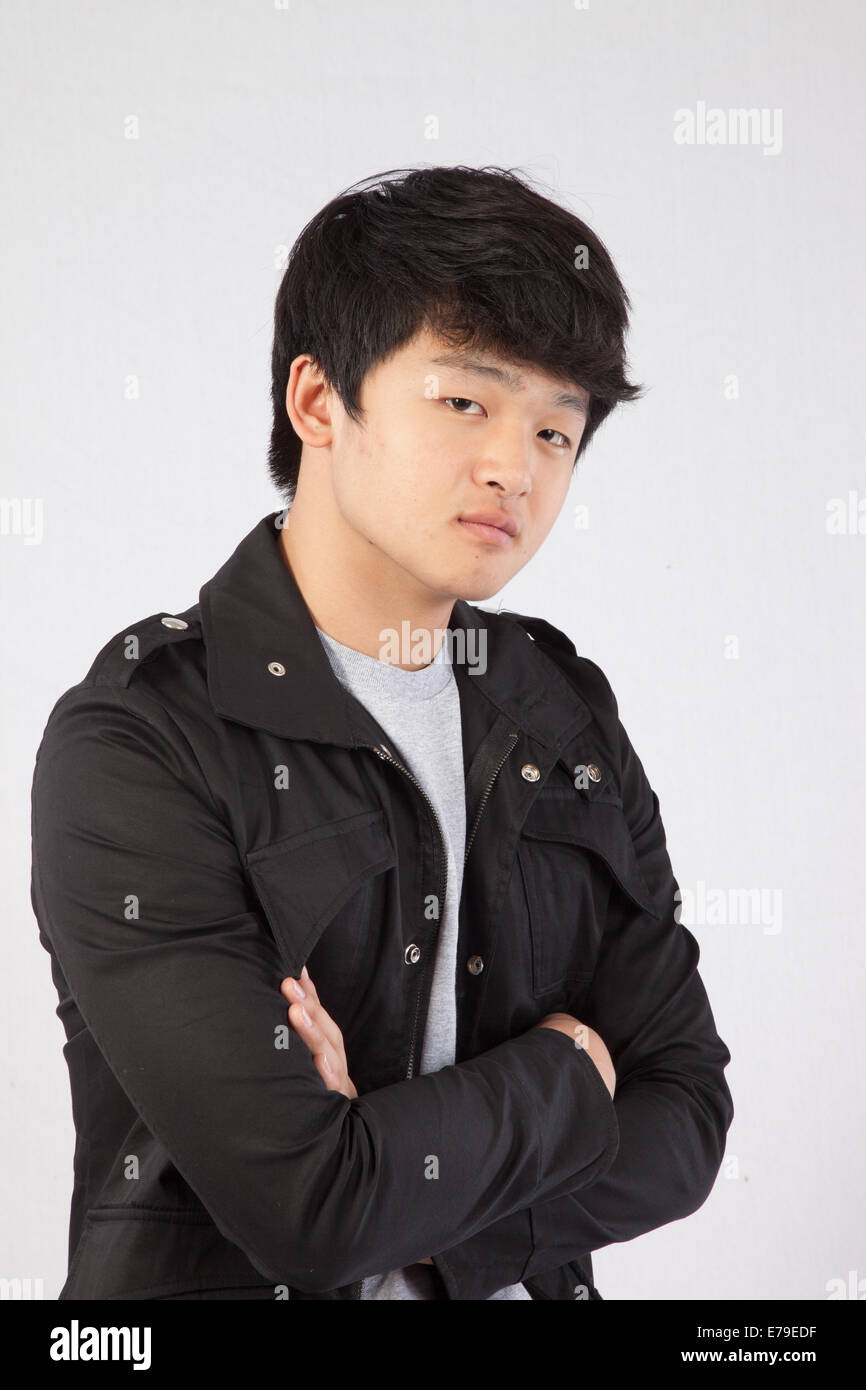 Handsome Asian man in a jacket and looking thoughtful with his arms ...