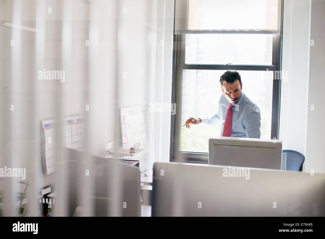A man standing over a desk looking at a computer screen Stock Photo - Alamy