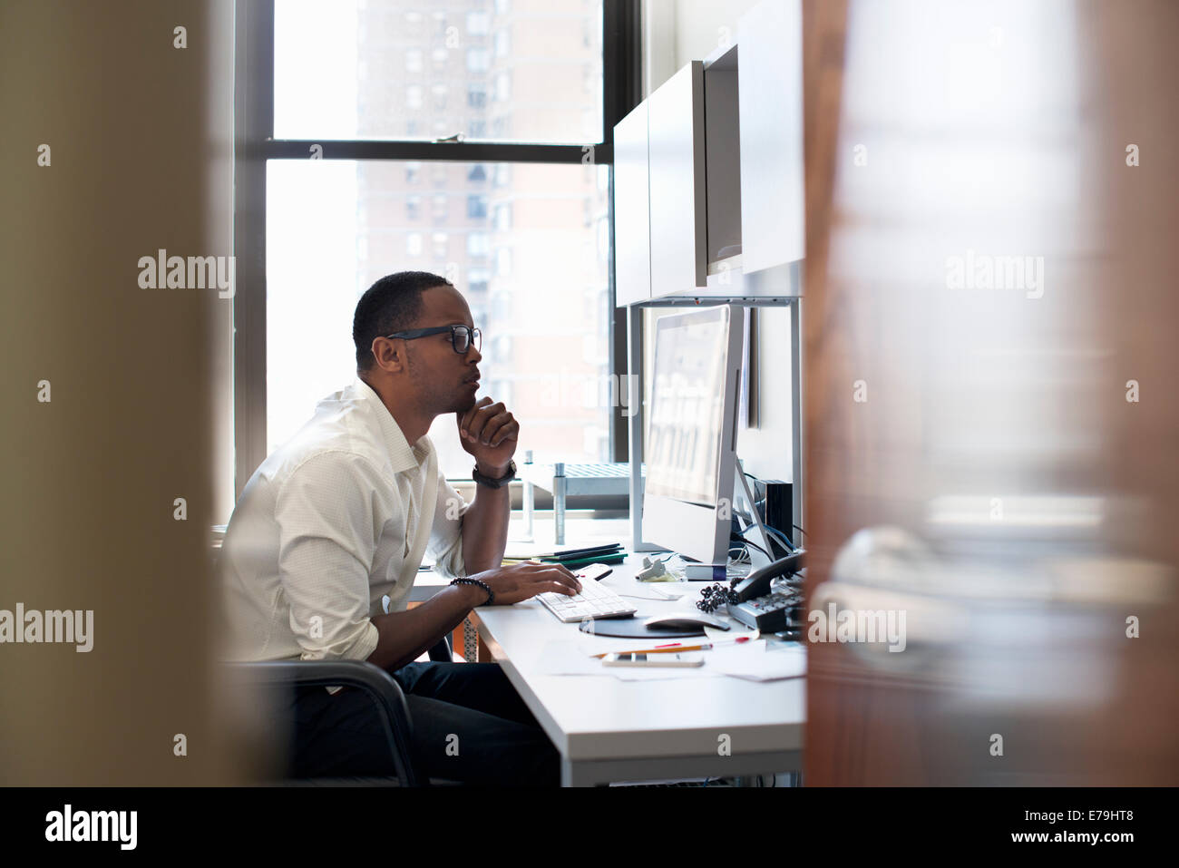 A man working in an office seated at a desk. Looking at a computer ...