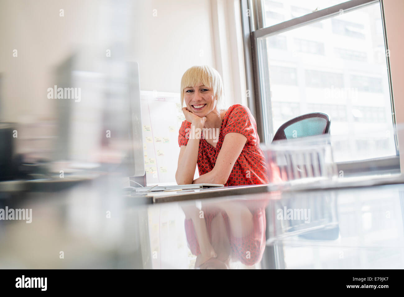Office life. A young woman sitting at an office desk, her chin resting ...