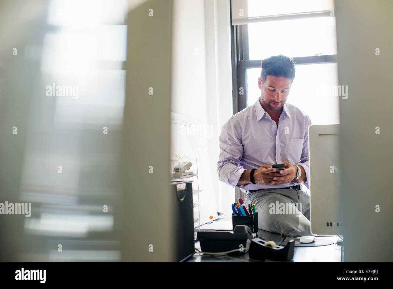 Office life. A man checking his phone in an office Stock Photo - Alamy