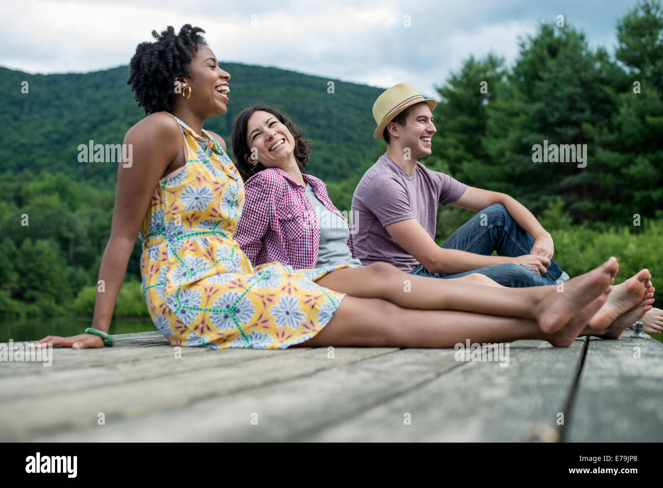 A group of people sitting on a woode pier overlooking a lake Stock ...