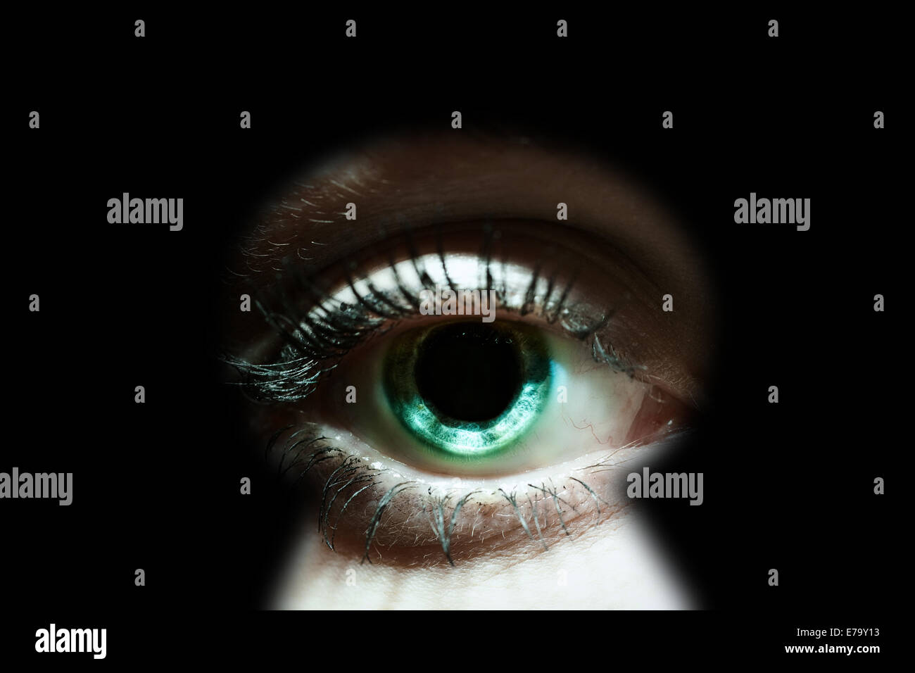 Womans eye peeking through a keyhole concept for curiosity, stalker ...