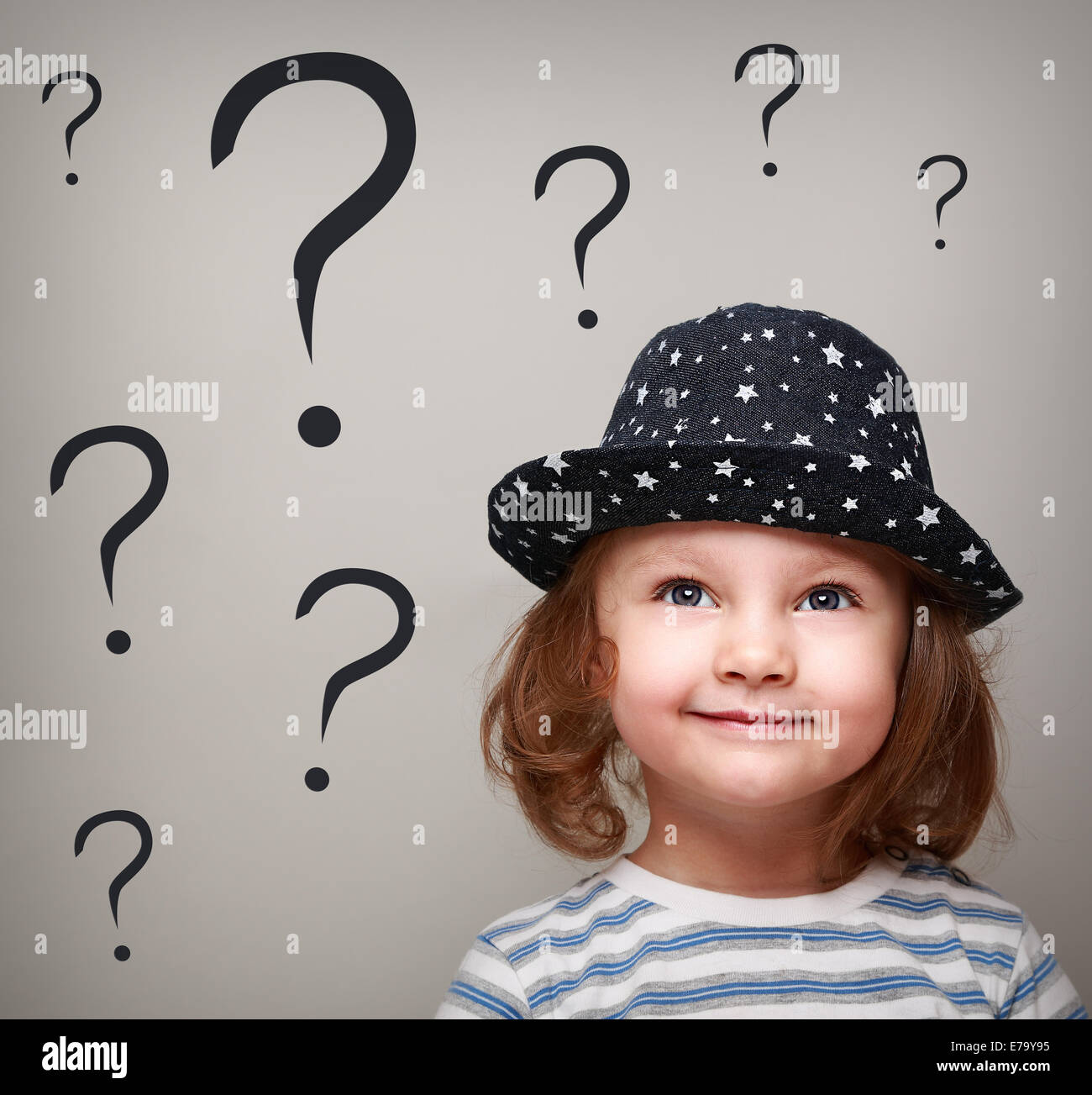 Happy thinking kid girl in hat looking up on many questions above the ...
