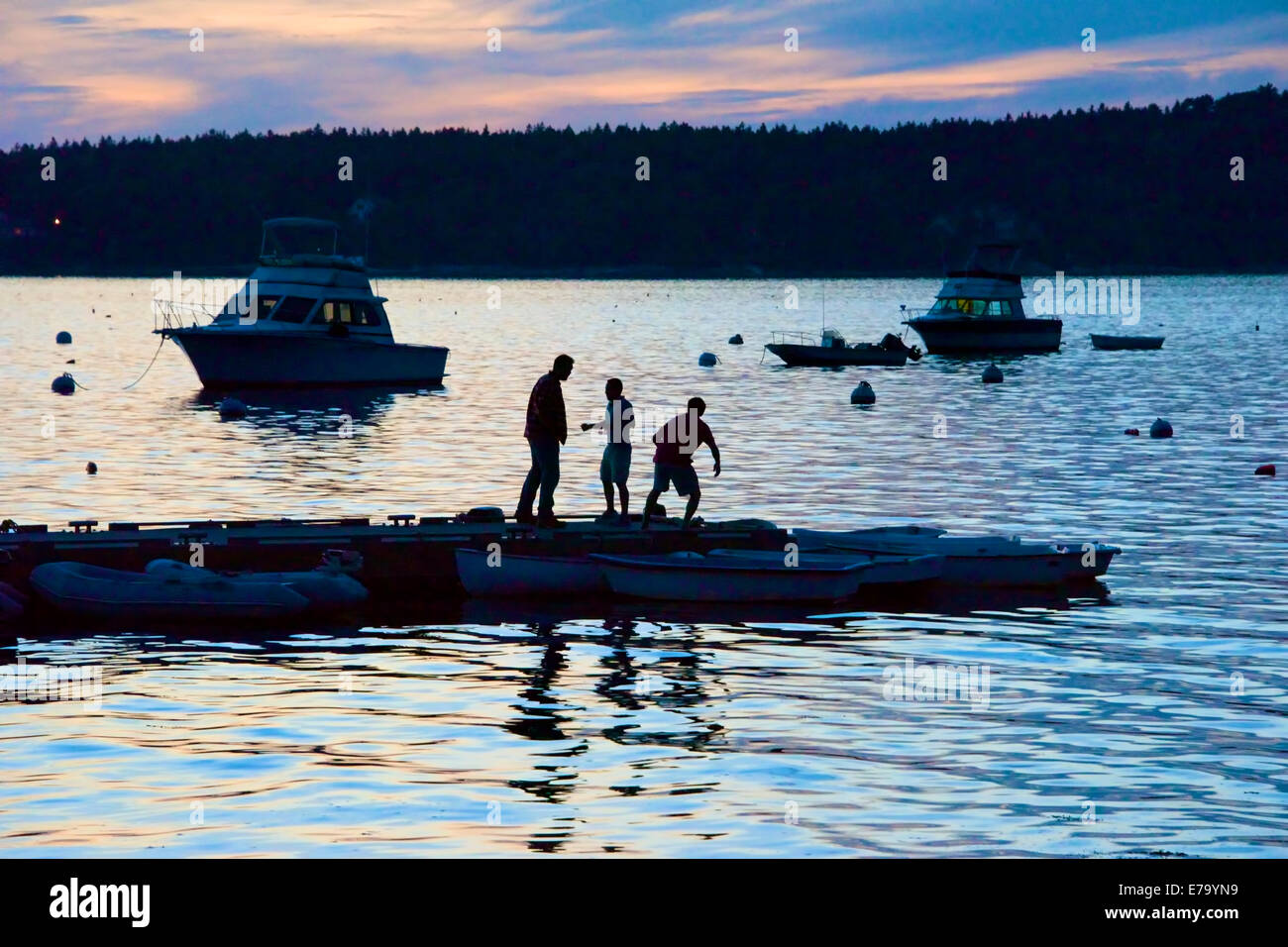 three people on a float in the bay at sunset Stock Photo - Alamy