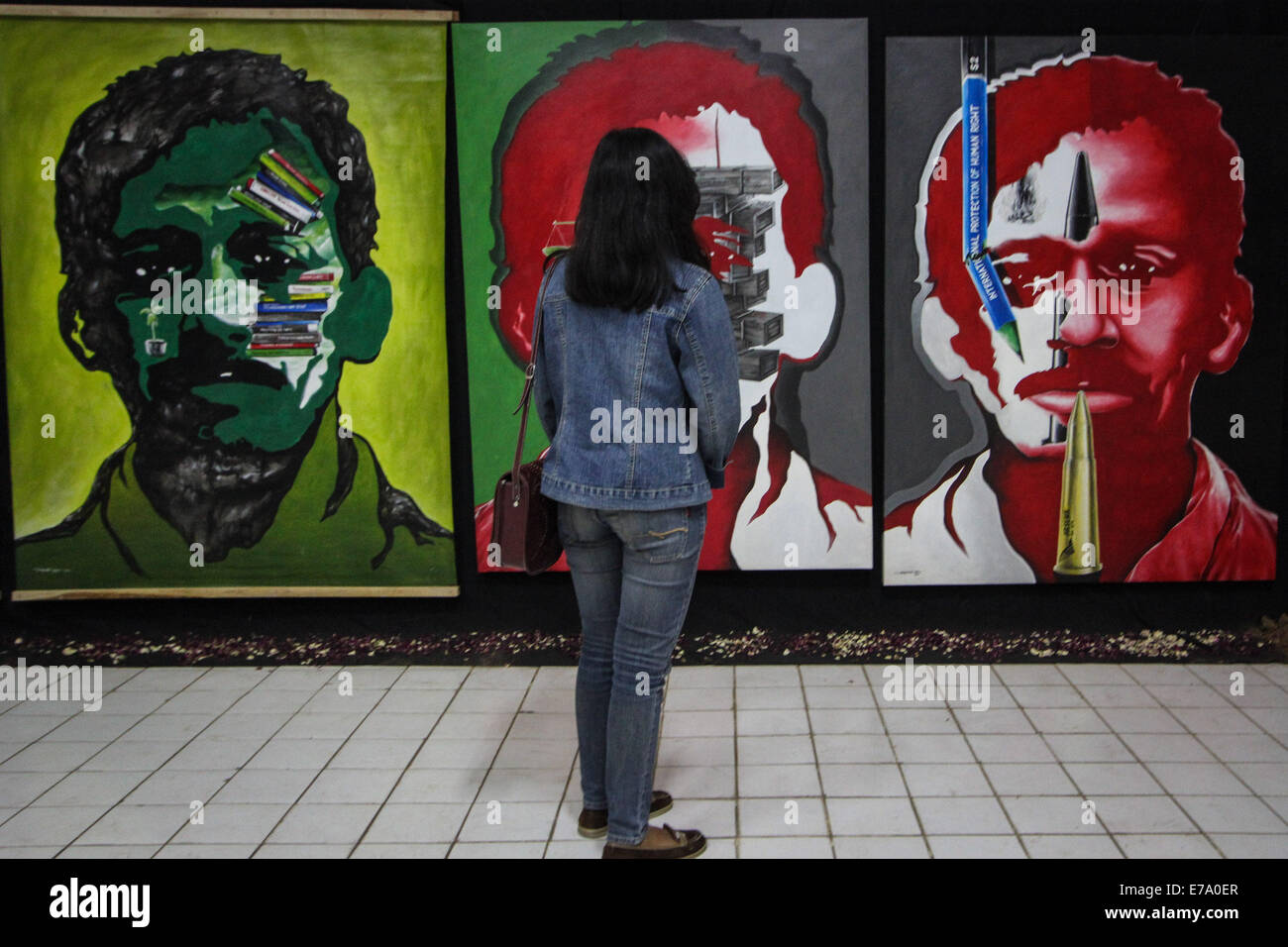 Visitor observes paintings by Munir, an Indonesian artists, during an ...