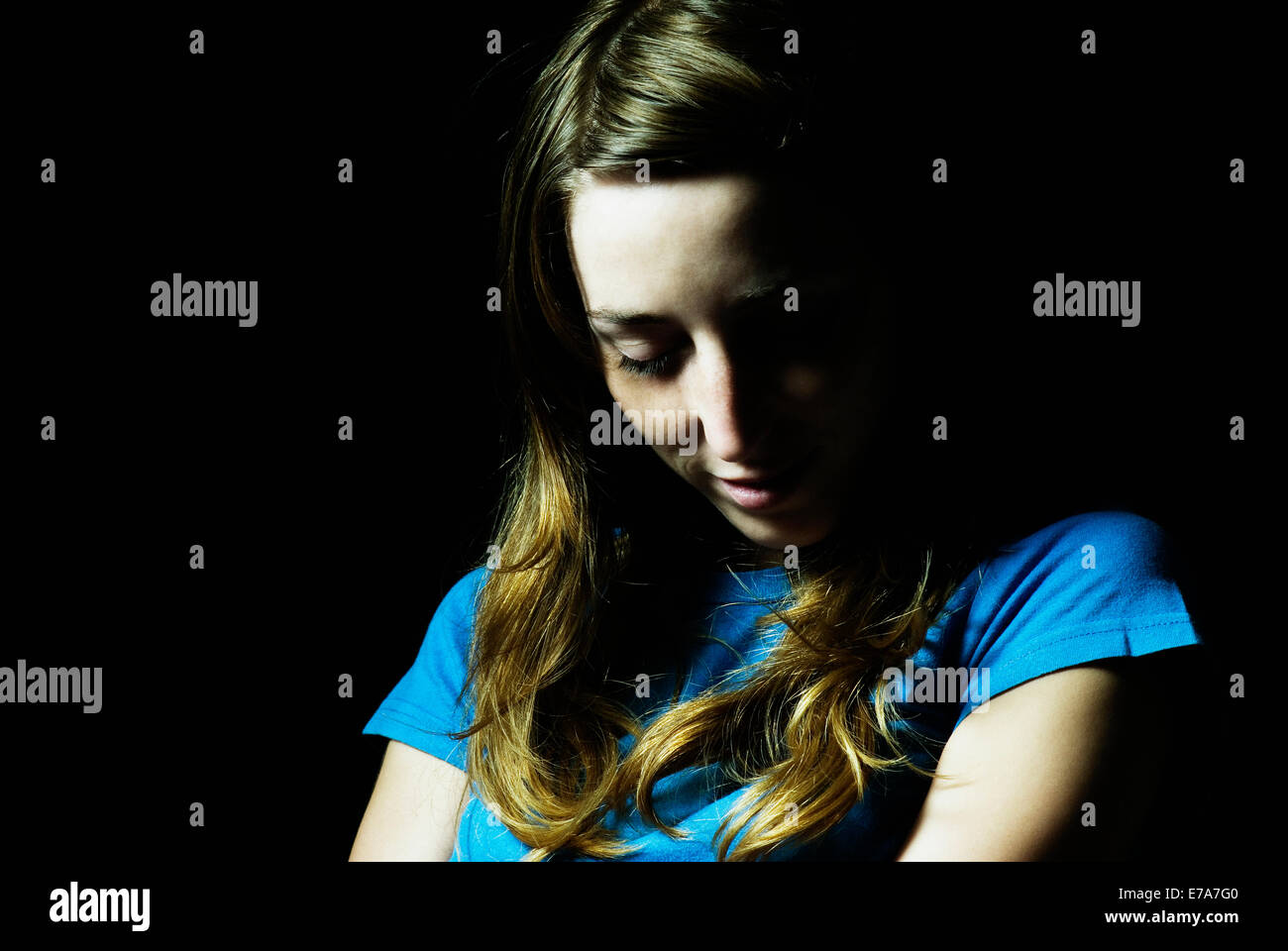 A young woman looking down and smiling coyly Stock Photo - Alamy