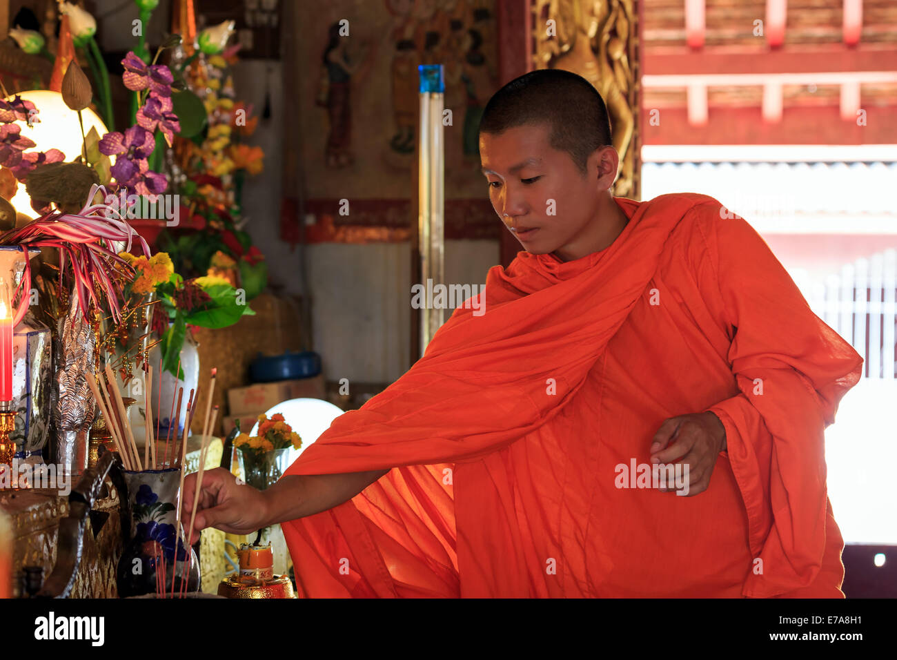 Young Buddhist Monk puts incense sticks in Laos temple Stock Photo - Alamy