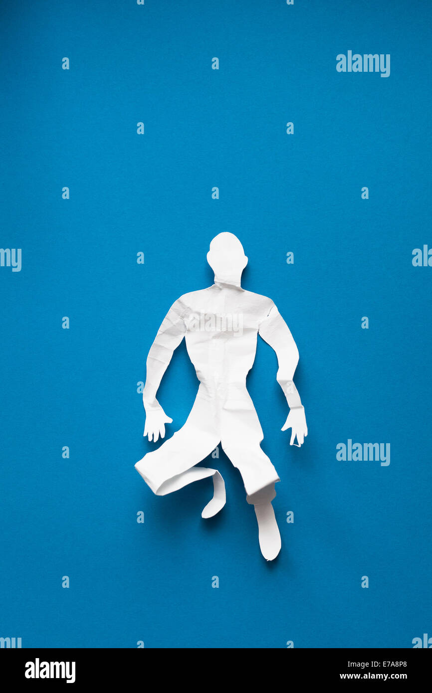 Directly above shot of crumpled paper man lying on blue background ...