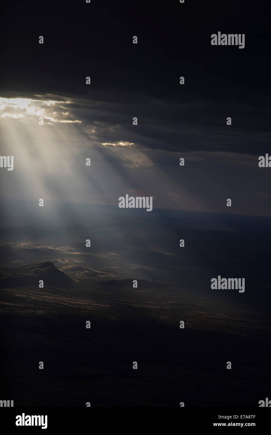 Sun streaming through storm clouds on arid landscape Stock Photo - Alamy