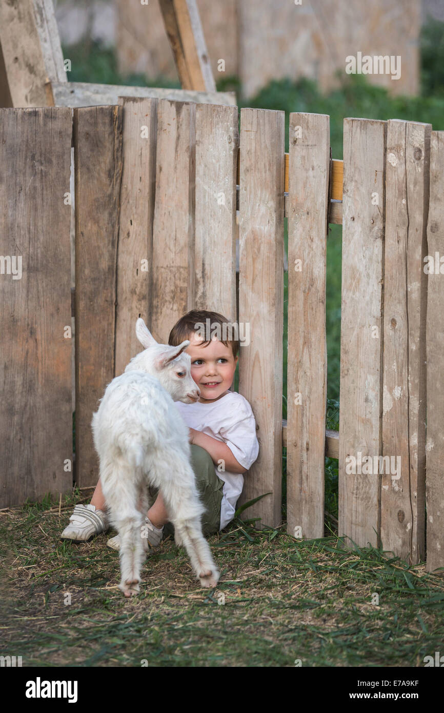 Cute boy with baby goat in park Stock Photo - Alamy