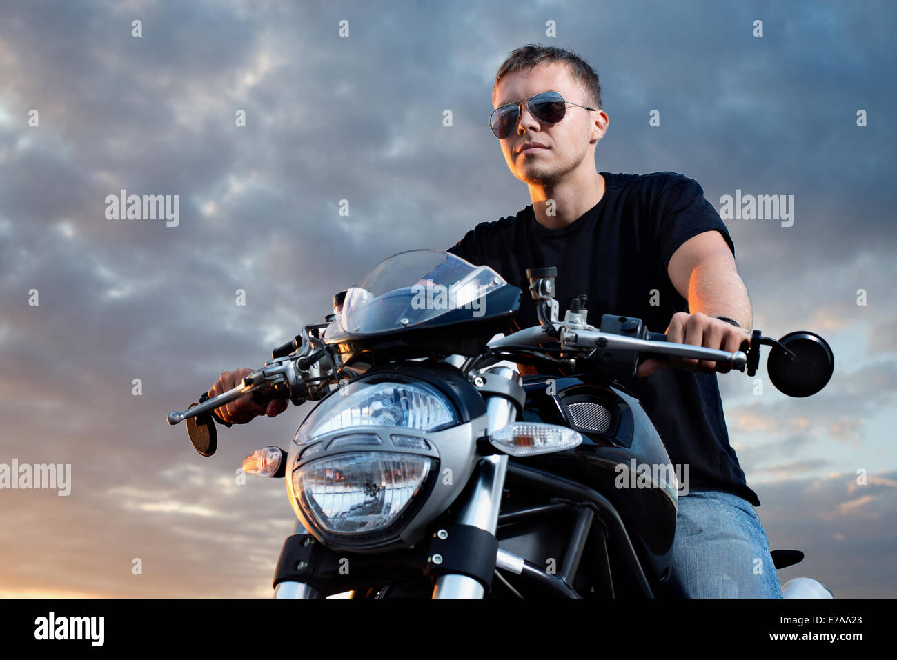 Romantic portrait handsome biker man in sunglasses sits on a bike on a ...