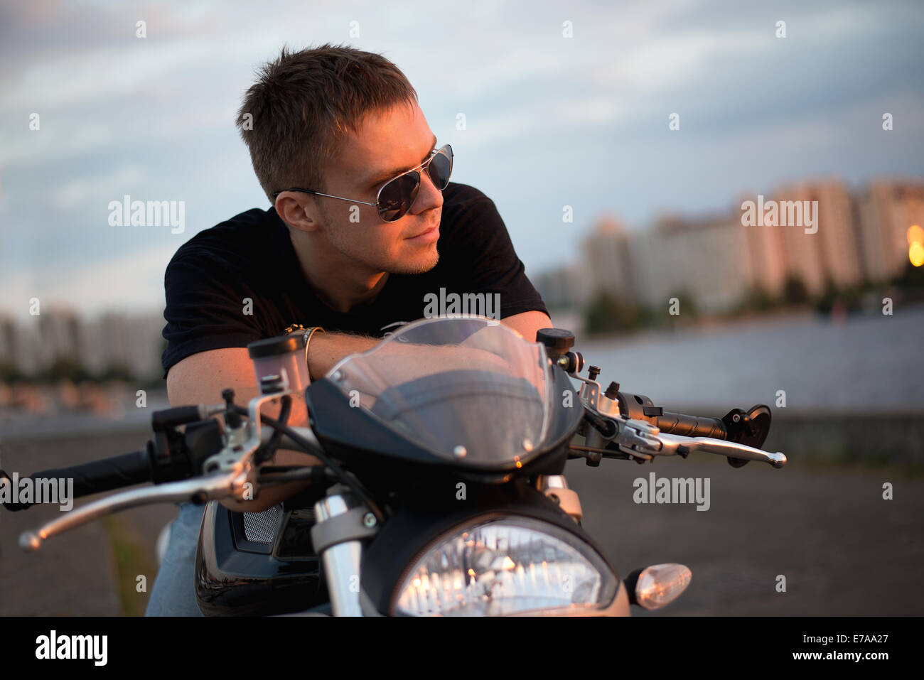 Romantic portrait handsome biker man in sunglasses sits on a bike on a ...