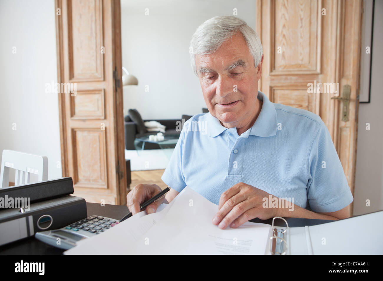 Senior man reviewing financial documents at table Stock Photo - Alamy