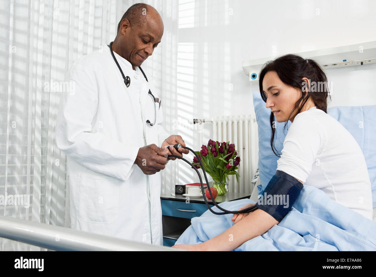 A doctor taking the blood pressure of a patient in a hospital Stock ...