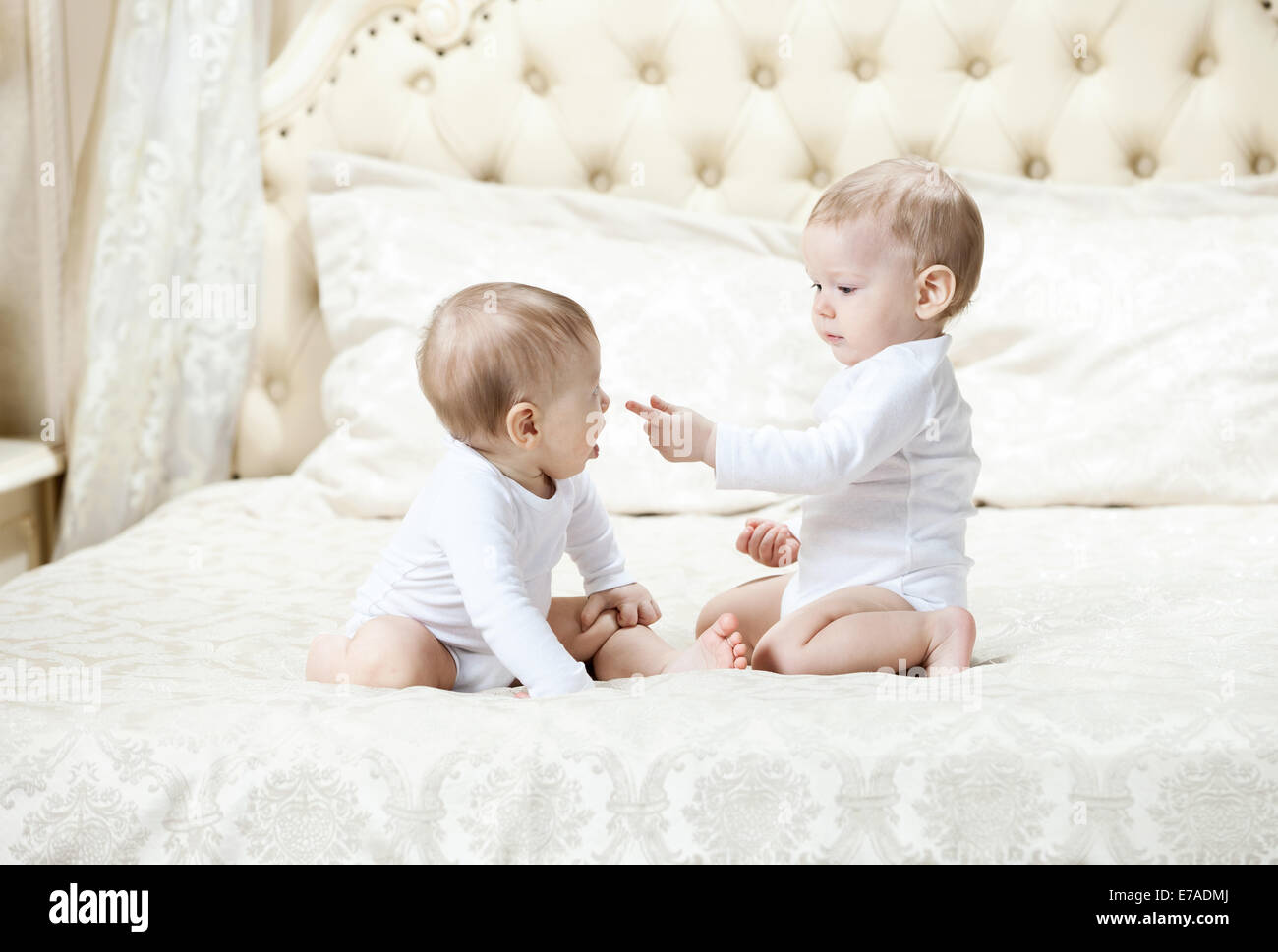 Two baby boys playing on bed at home Stock Photo - Alamy