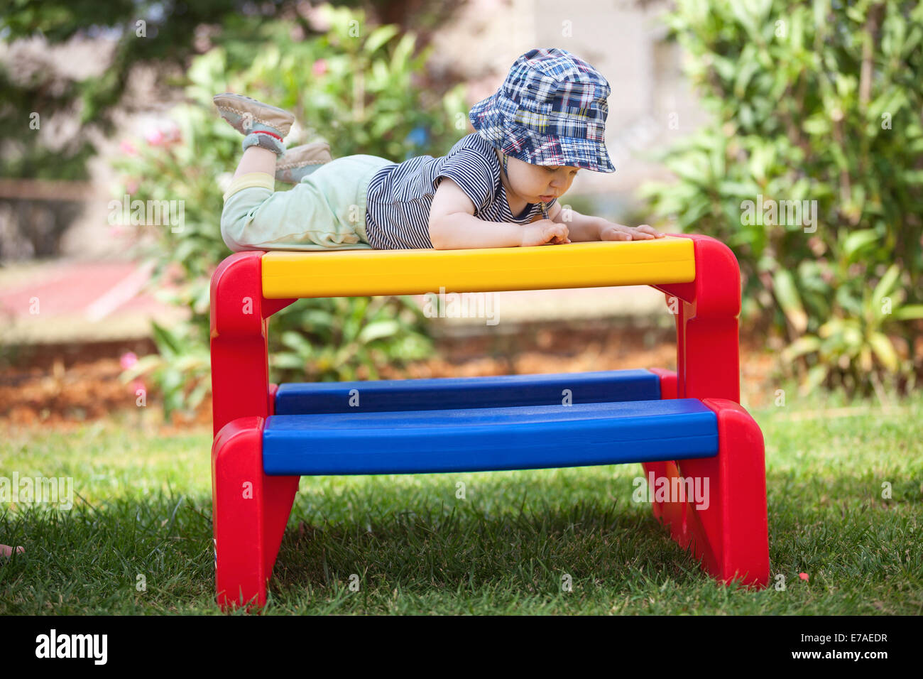 Toddler boy playing while lying on kids table outdoors Stock Photo - Alamy