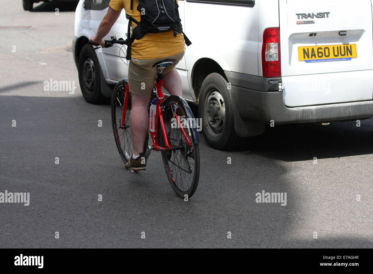 A cyclist riding alongside a white van in London Stock Photo - Alamy