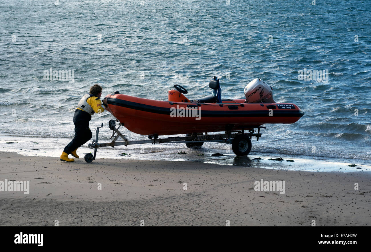 An RNLI volunteer pushes a boat trailer into the sea to launch an ...