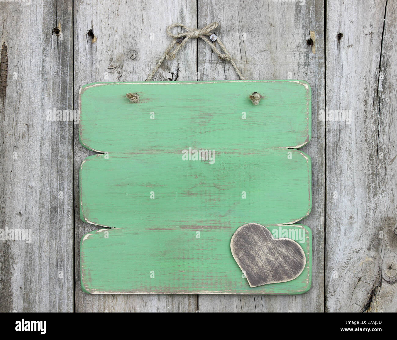 Blank green sign with wooden heart hanging on old weathered wood door ...