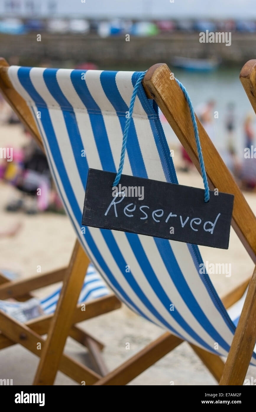 A deck chair with a reserved sign at Harbour beach in St Ives, Cornwall ...