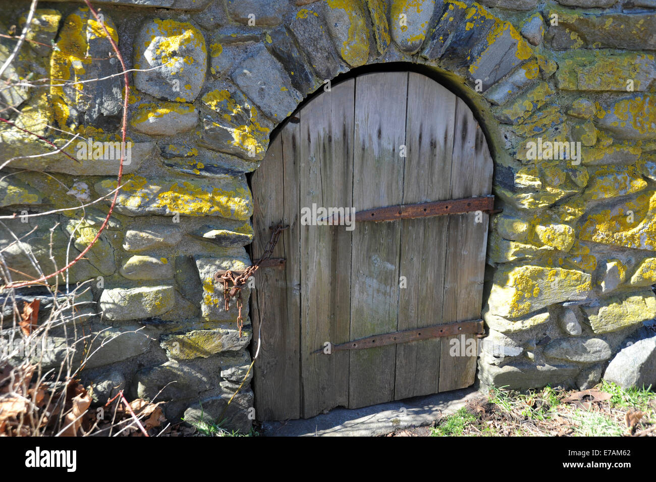 Old lichen-covered stone spring house with wooden door on rusted hinges ...