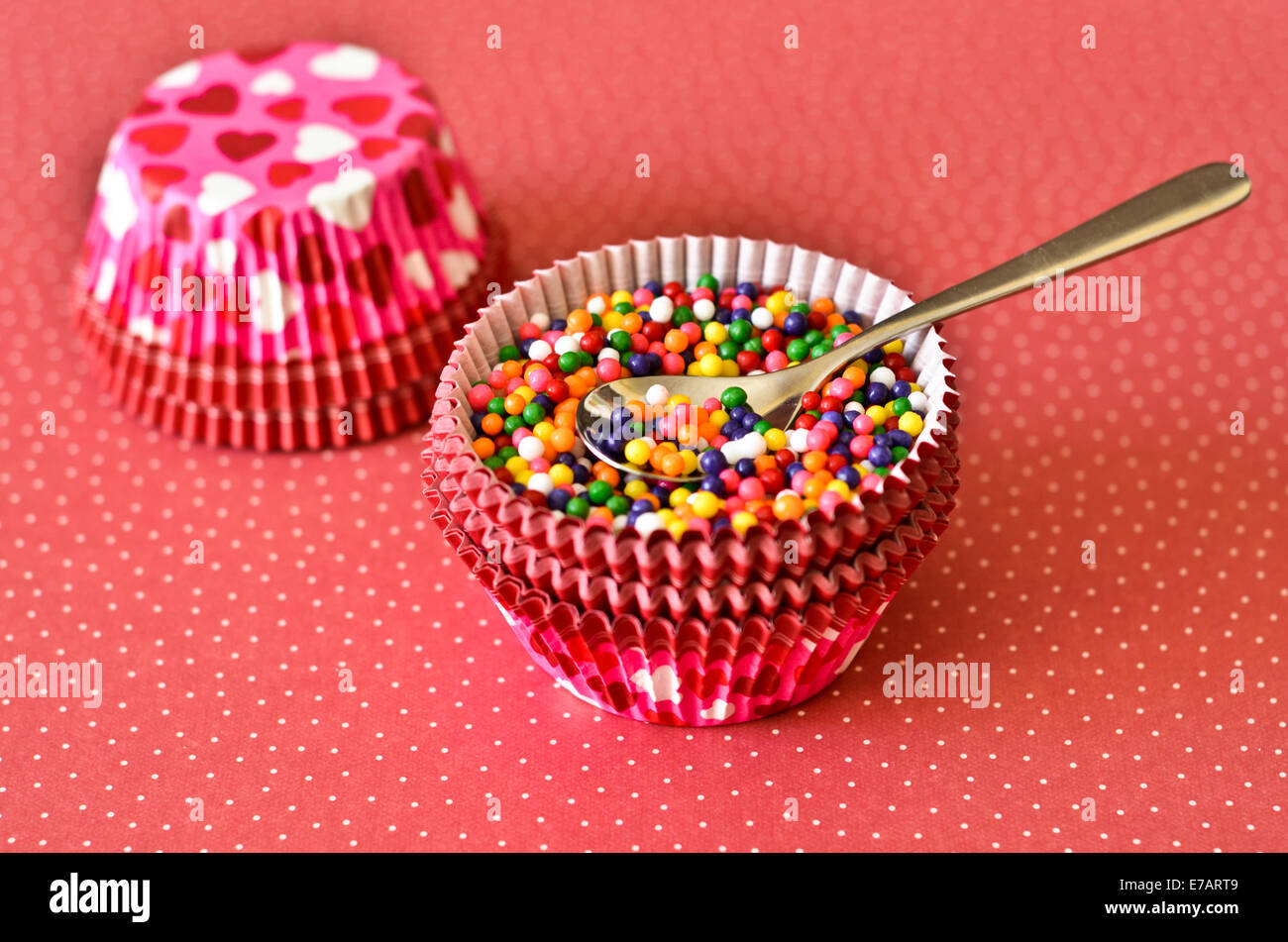 Colorful sprinkles in red paper cups on red background Stock Photo - Alamy