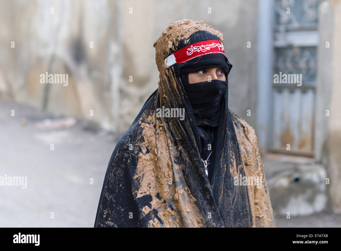 Young Shiite Muslim woman, wearing a black chador covered with mud ...