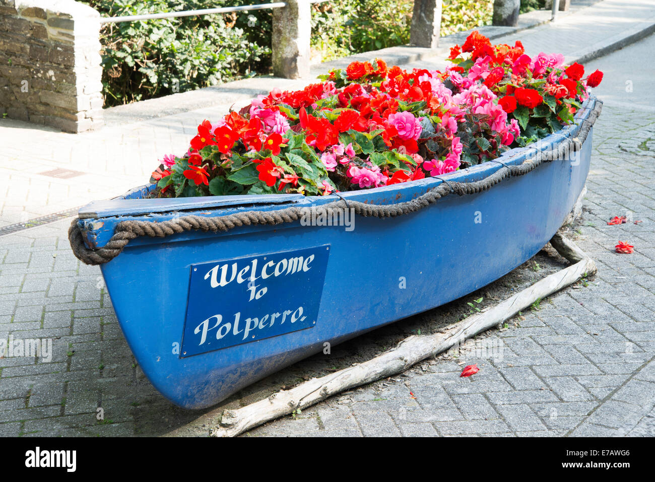blue boat with red and pink flowers and "Welcome to Polperro" sign ...