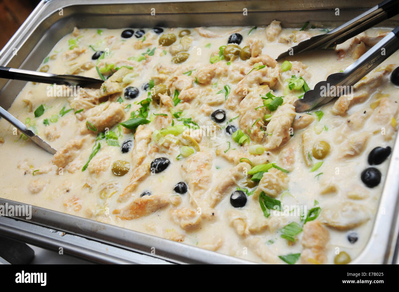 Chicken with olives and a white cream sauce being served at a buffet ...