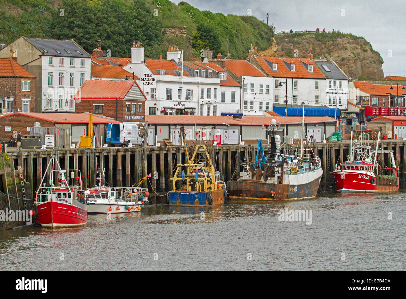 Colourful fishing boats moored in Whitby harbour with buildings of ...