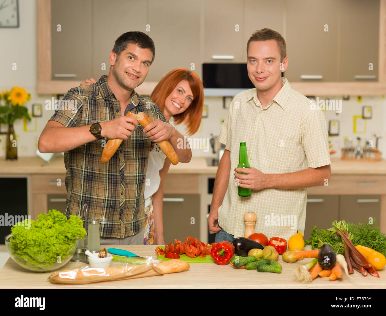 group of young people standing and having fun in kitchen, preparing ...
