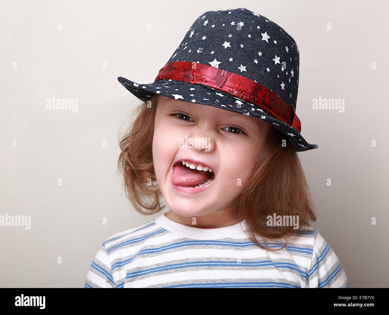 Funny grimacing kid in hat showing the tongue Stock Photo - Alamy
