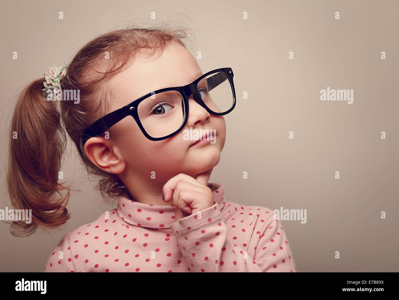 Thinking kid girl in glasses looking happy. Closeup instagram effect ...