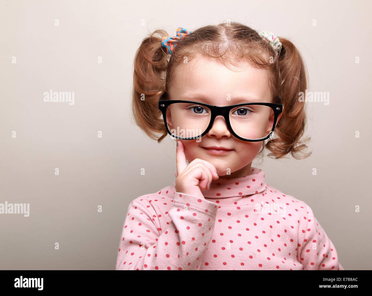 Thinking kid girl in glasses looking happy on copy space background ...