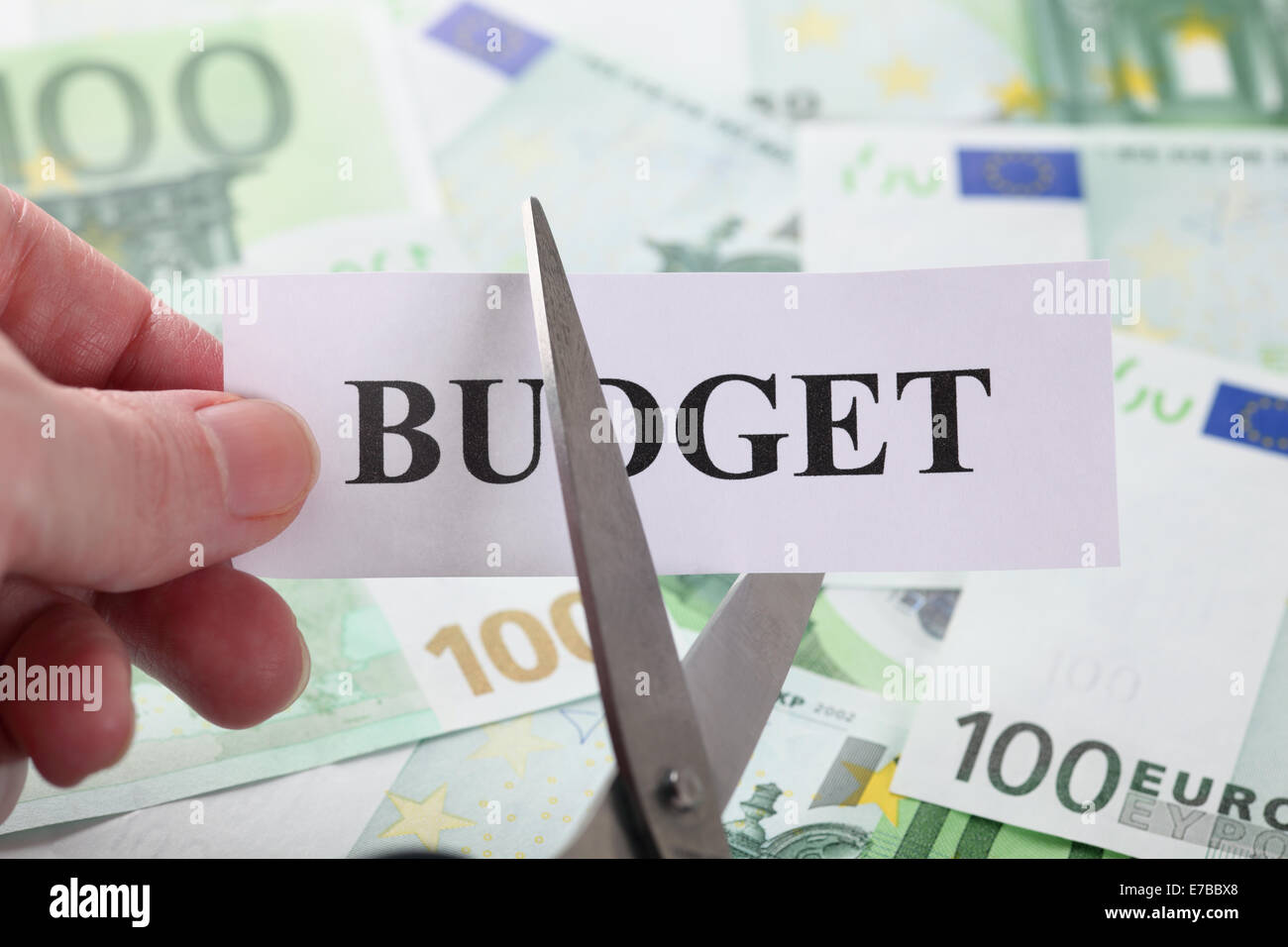 Budget cut. Hand with scissors cutting the word "Budget" on euro ...