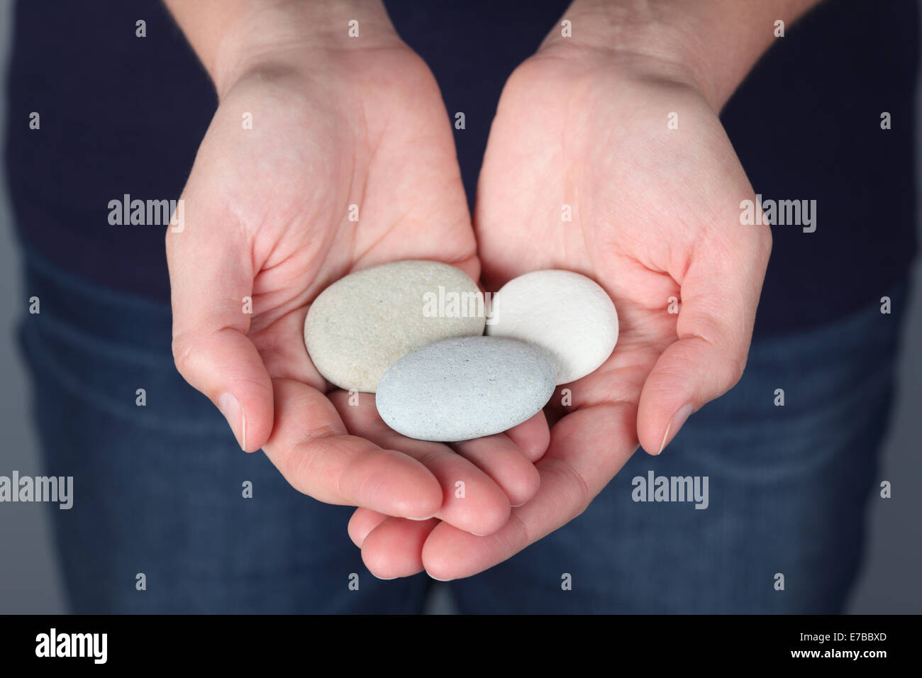 Woman's hands holding three stones Stock Photo - Alamy