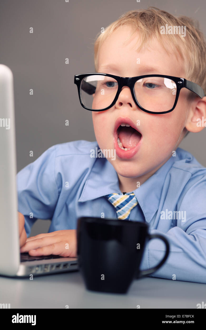 A young cute boy uses a laptop computer in his office. He's 3 years old ...