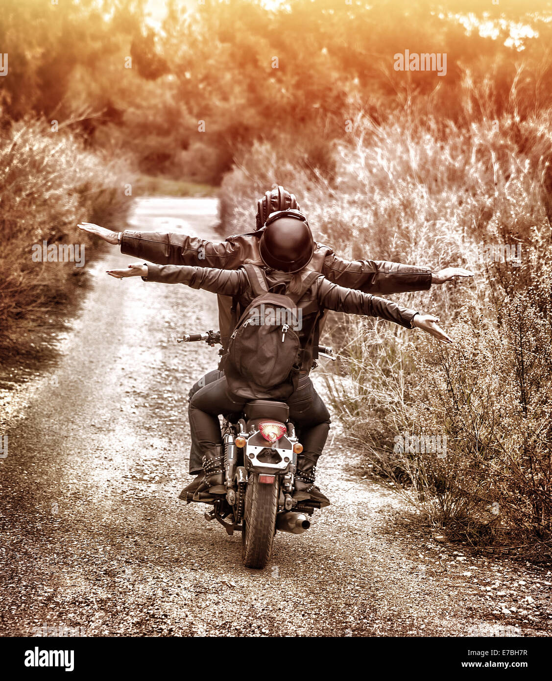 Vintage style image, rear view of two happy bikers riding on the road ...