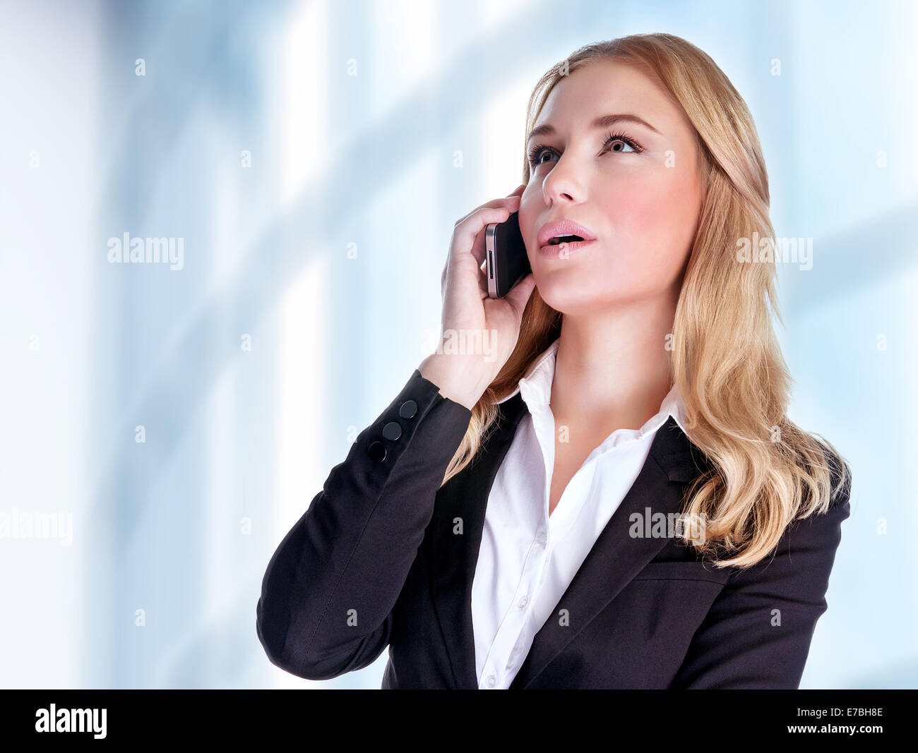 Serious woman talking on mobile phone near office building ...