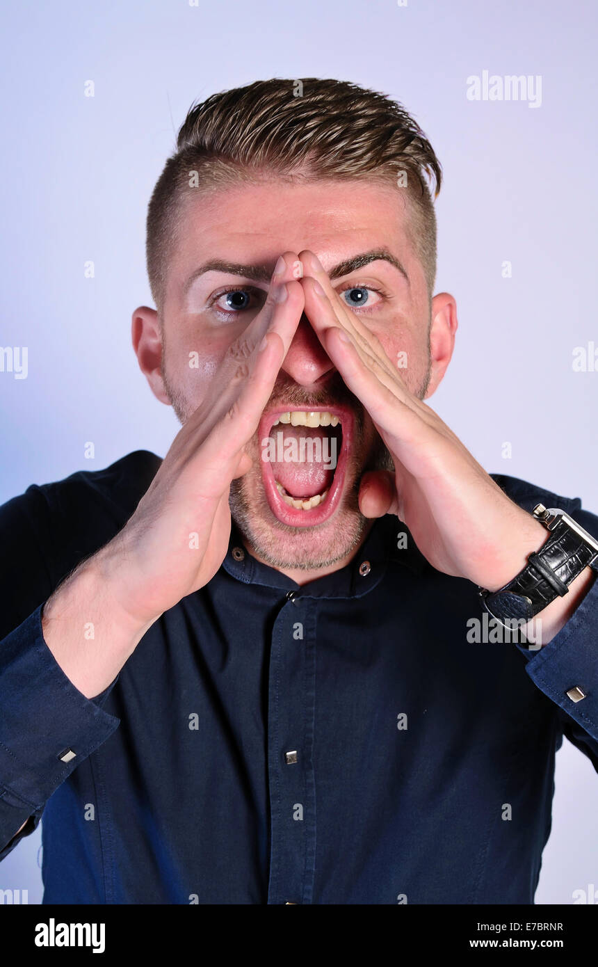 young man yelling nervous on blue background Stock Photo - Alamy