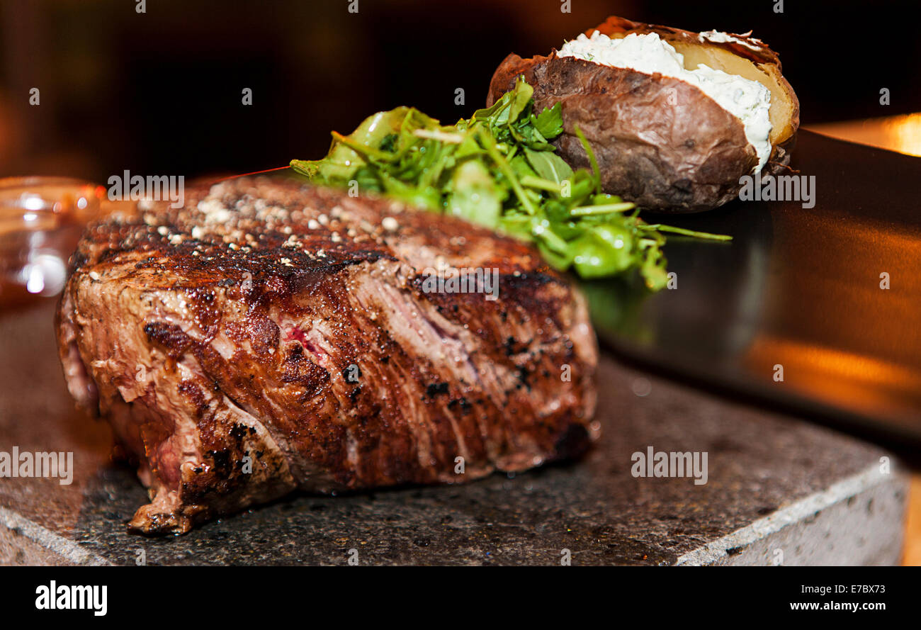 Rare or medium rare steak, T-bone, sirloin on a stone with baked potato ...