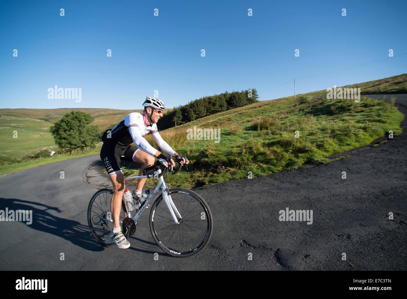 Cyclist climbing a steep incline in the Yorkshire Dales National Park ...